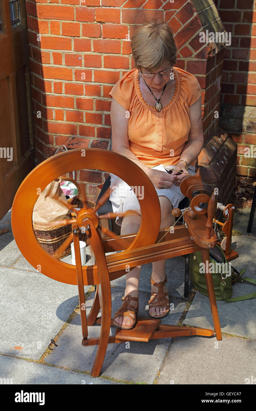 A lady sitting by her spinning wheel "teasing" out the wool ready to go ...