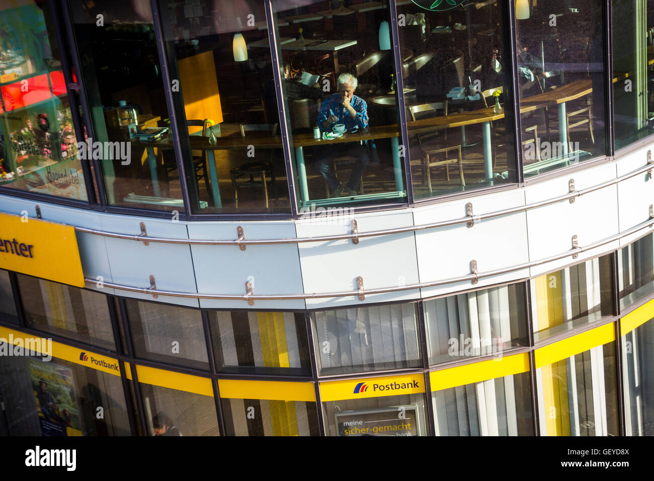 A man relaxing in a window seat at a shopping mall cafe in Steglitz ...