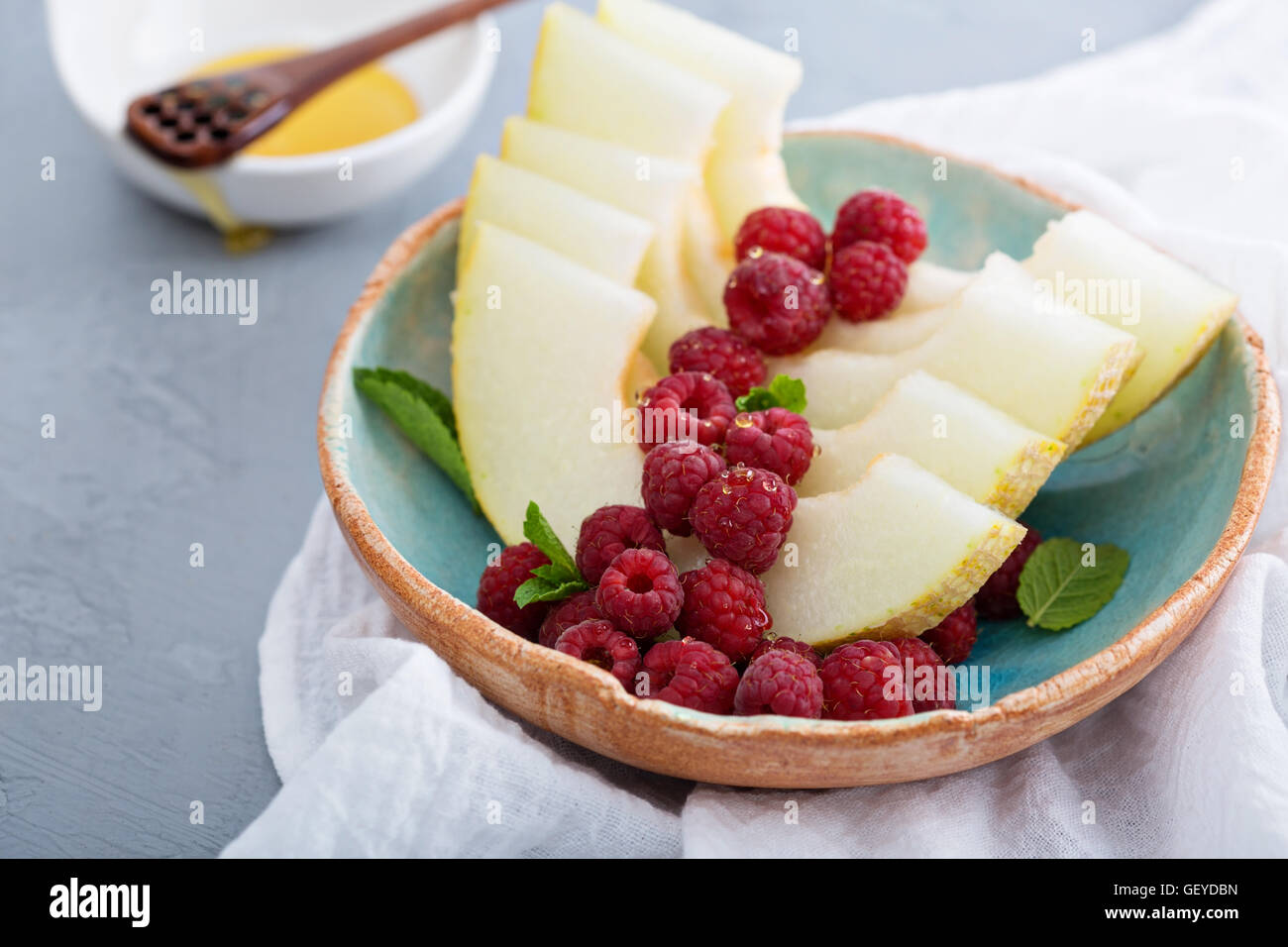 Melon slices served with raspberry and honey Stock Photo - Alamy