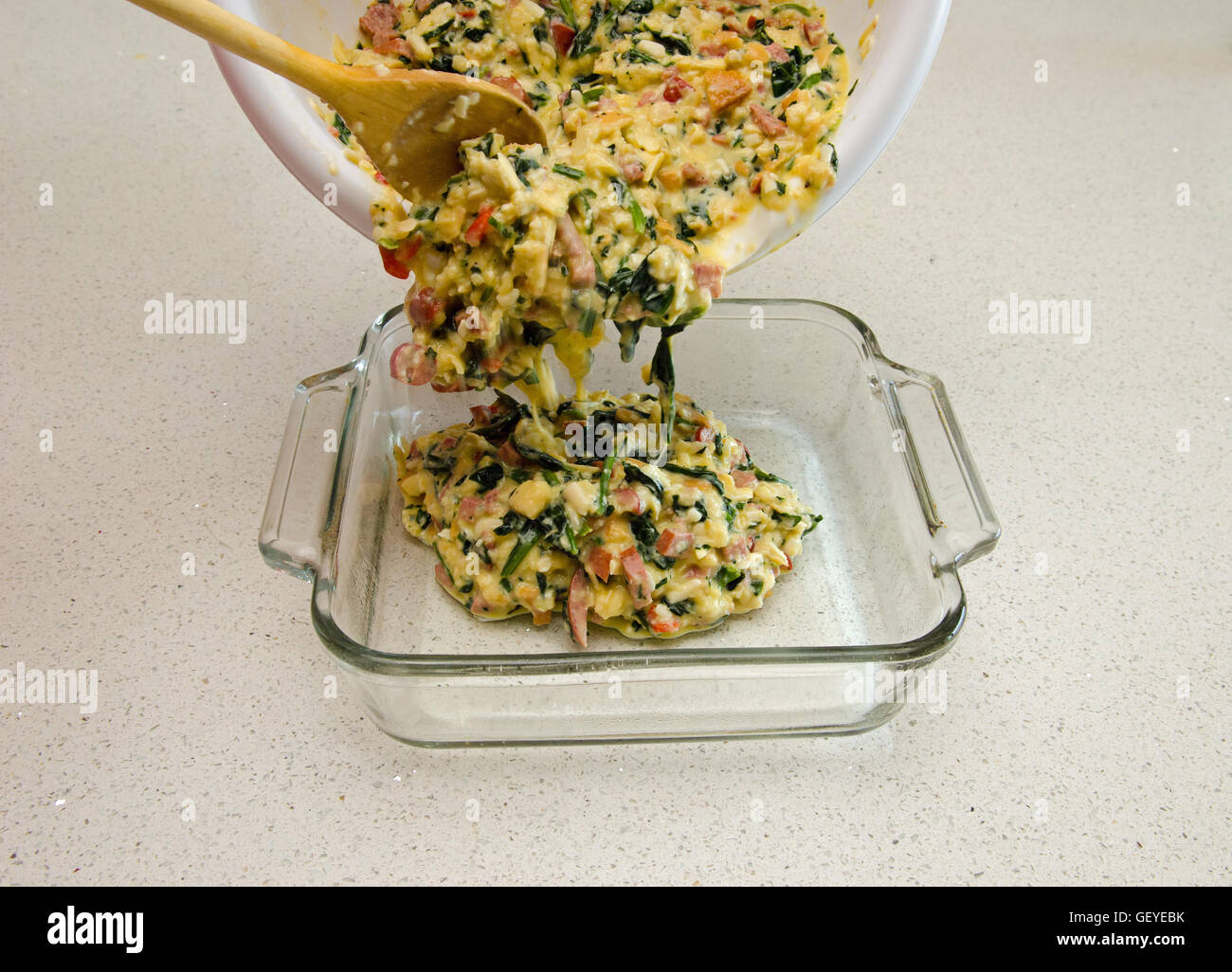 Food preparation showing casserole mixture being poured into a baking ...
