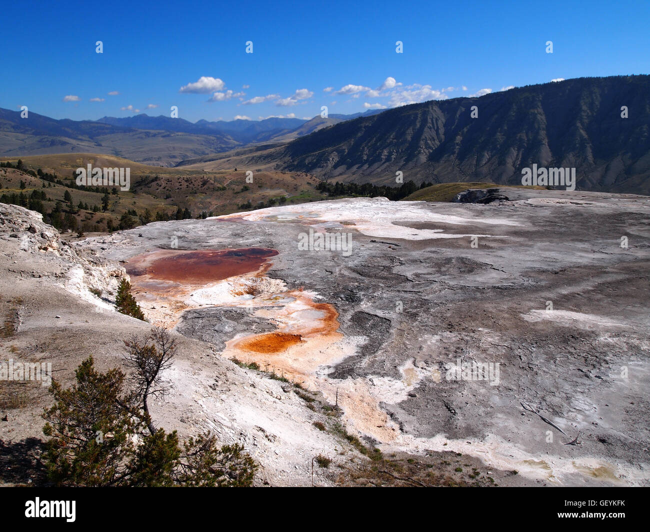 Dried up field with mineral deposits and rock exposed. Hills and blue ...
