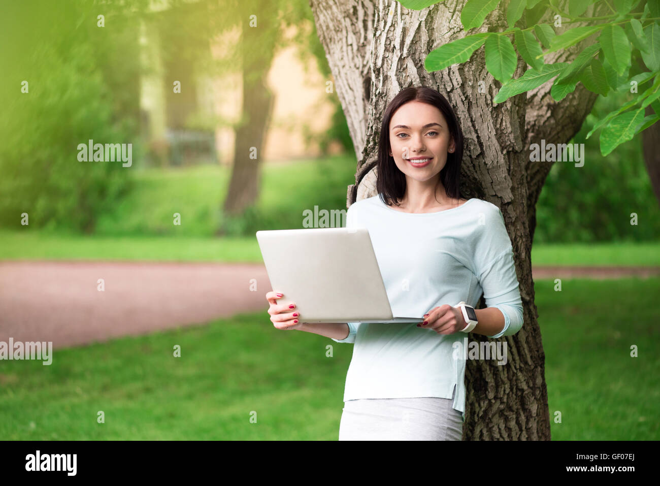 Positive woman standing under the tree Stock Photo - Alamy
