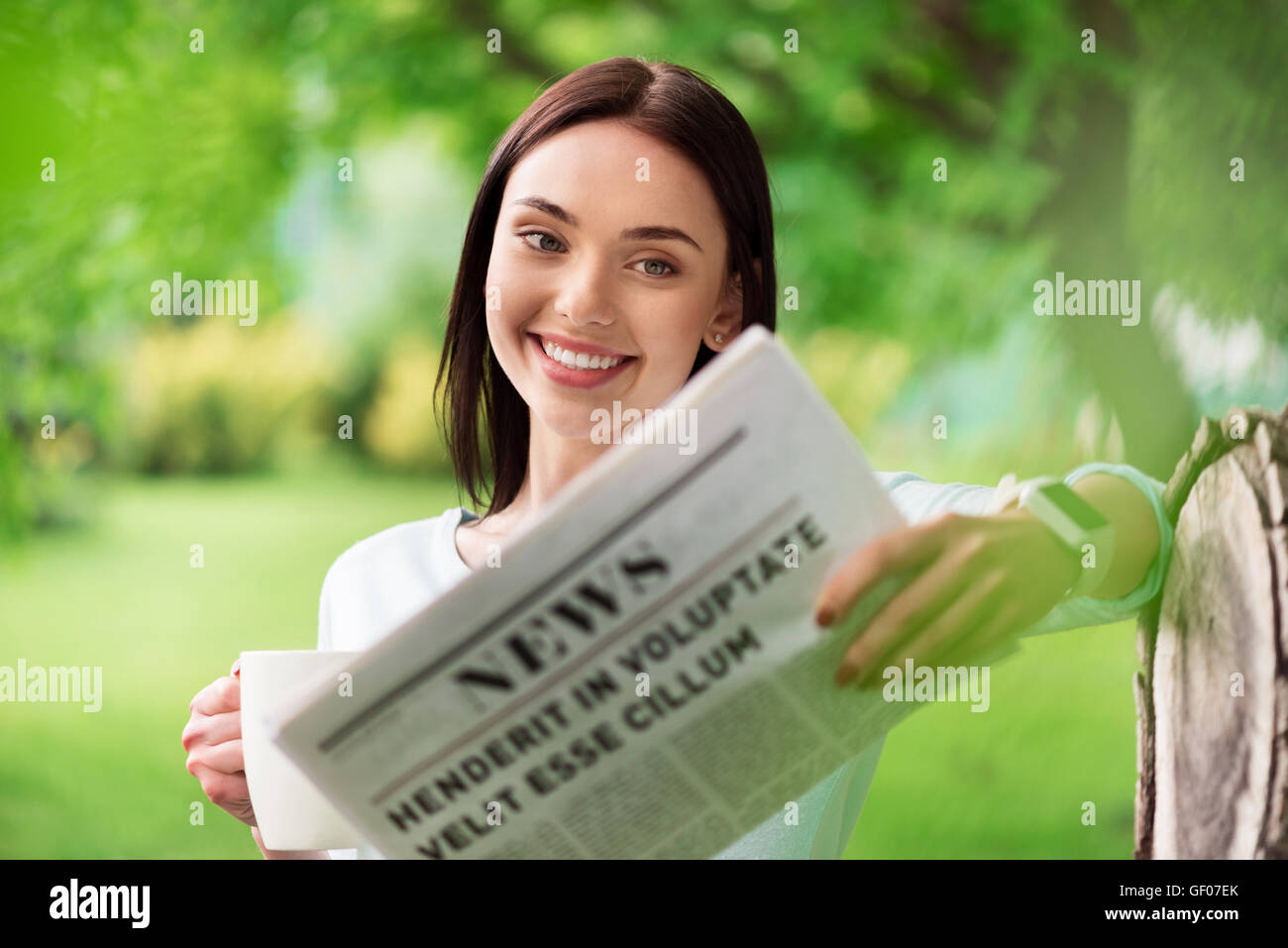 Positive woman standing under the tree Stock Photo - Alamy