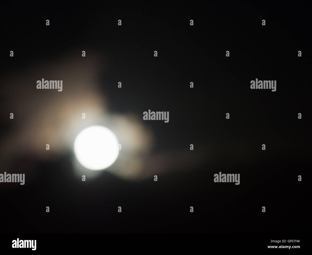 Blurry defocused moonscape background of a full moon behind clouds ...