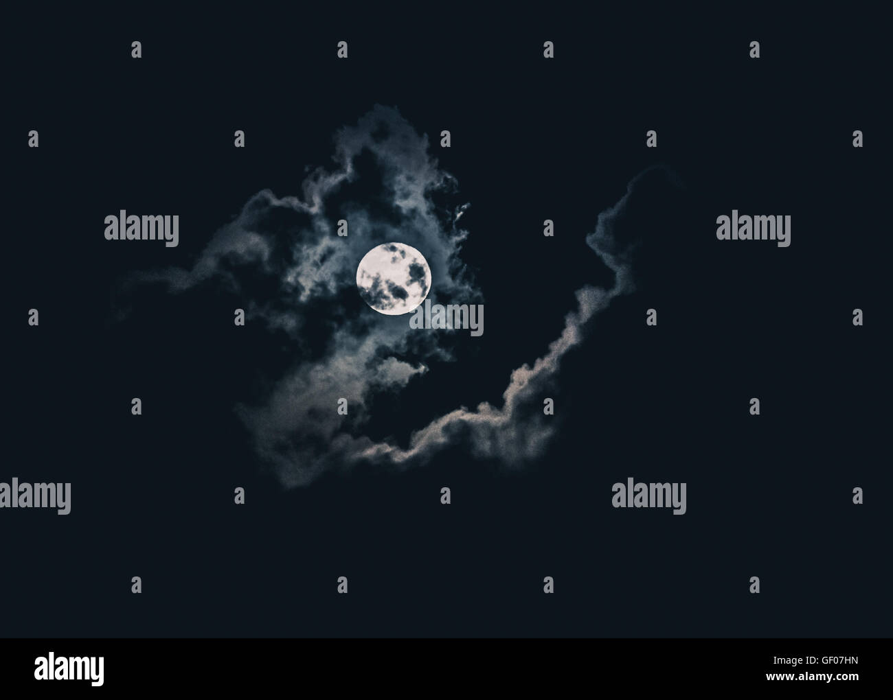 Full moon behind clouds glowing on a dark night sky Stock Photo - Alamy