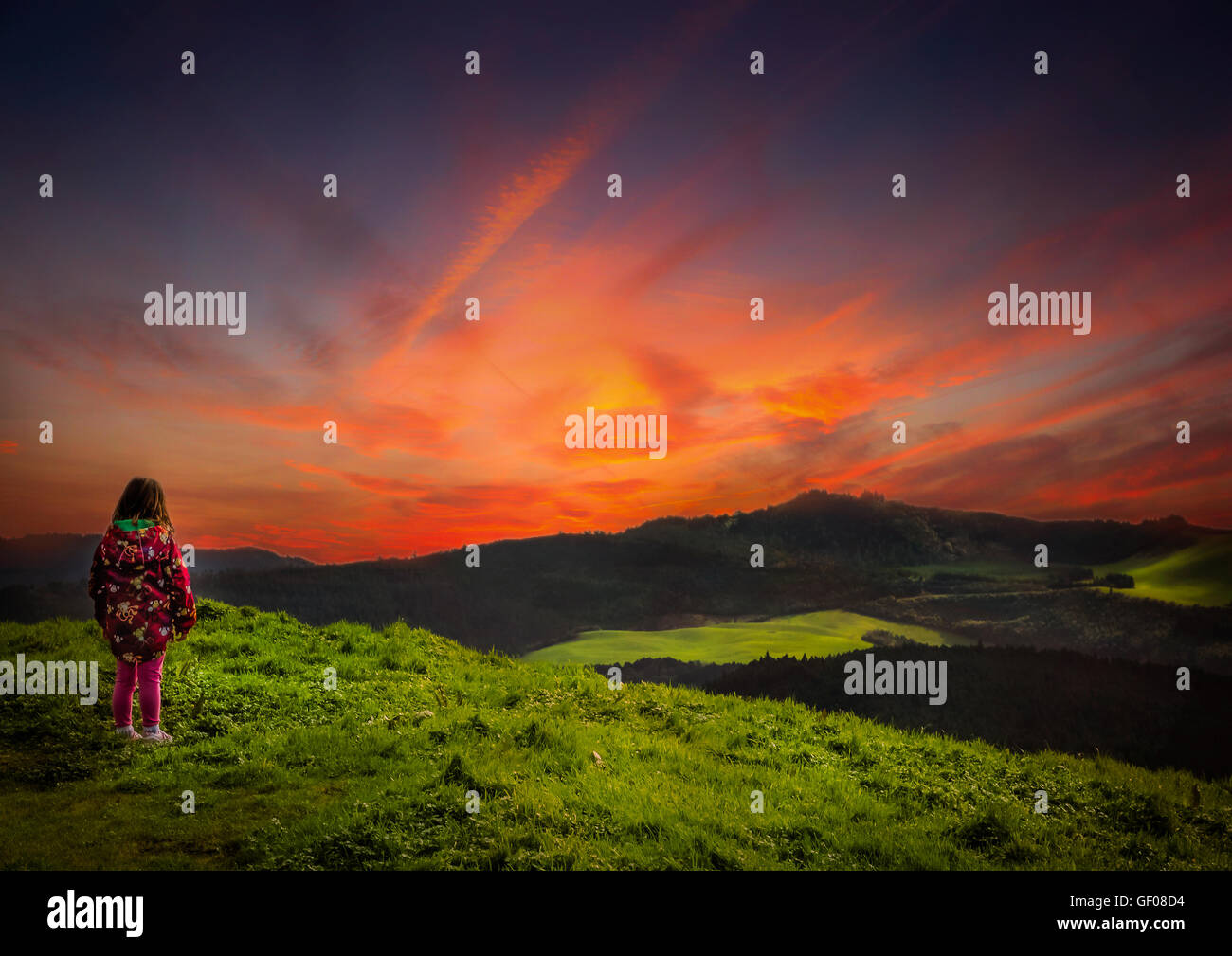 Little girl standing on a hill and admiring the stunning sunset over ...