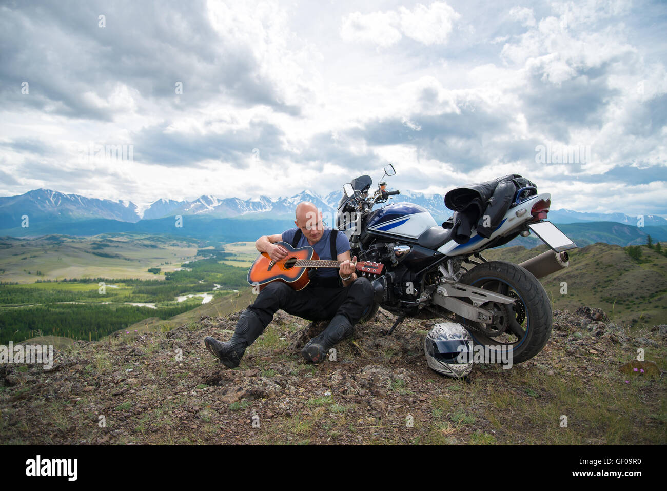 bald motorcyclist plays guitar sitting on a motorcycle the ba Stock ...