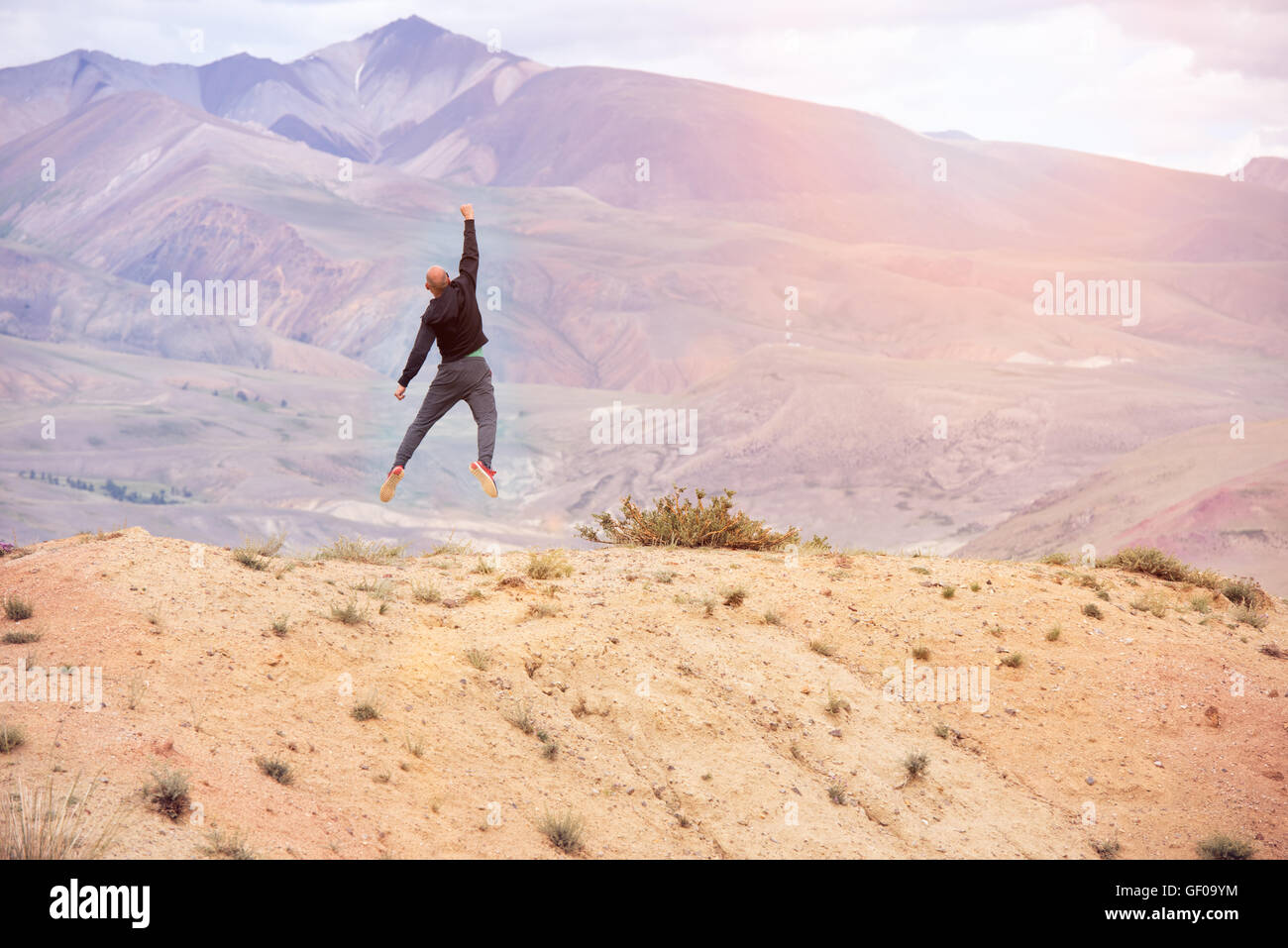 bald man jumping on top of a mountain Stock Photo - Alamy