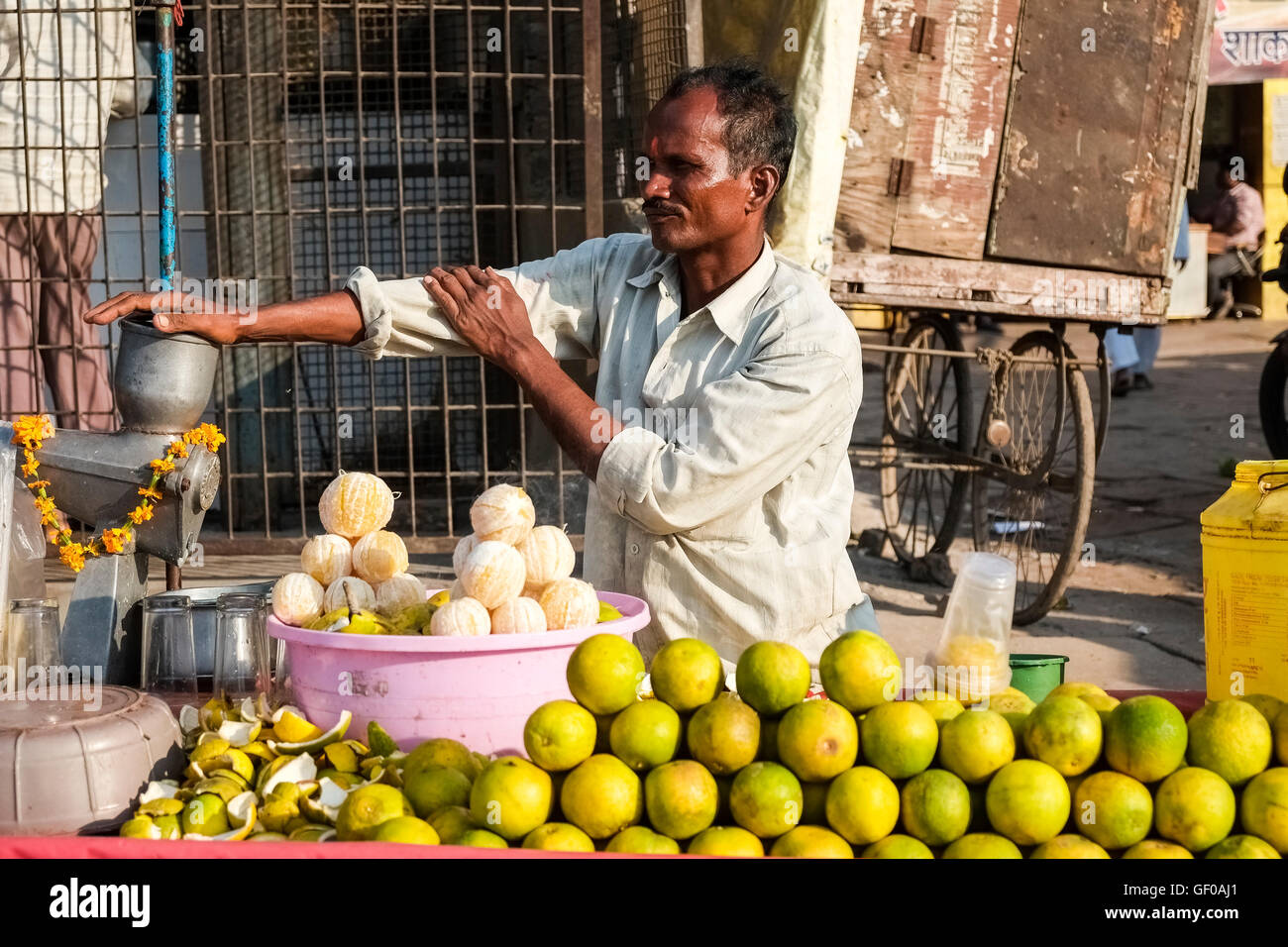 A man at his fresh orange juice stall at a street market in Varanasi ...