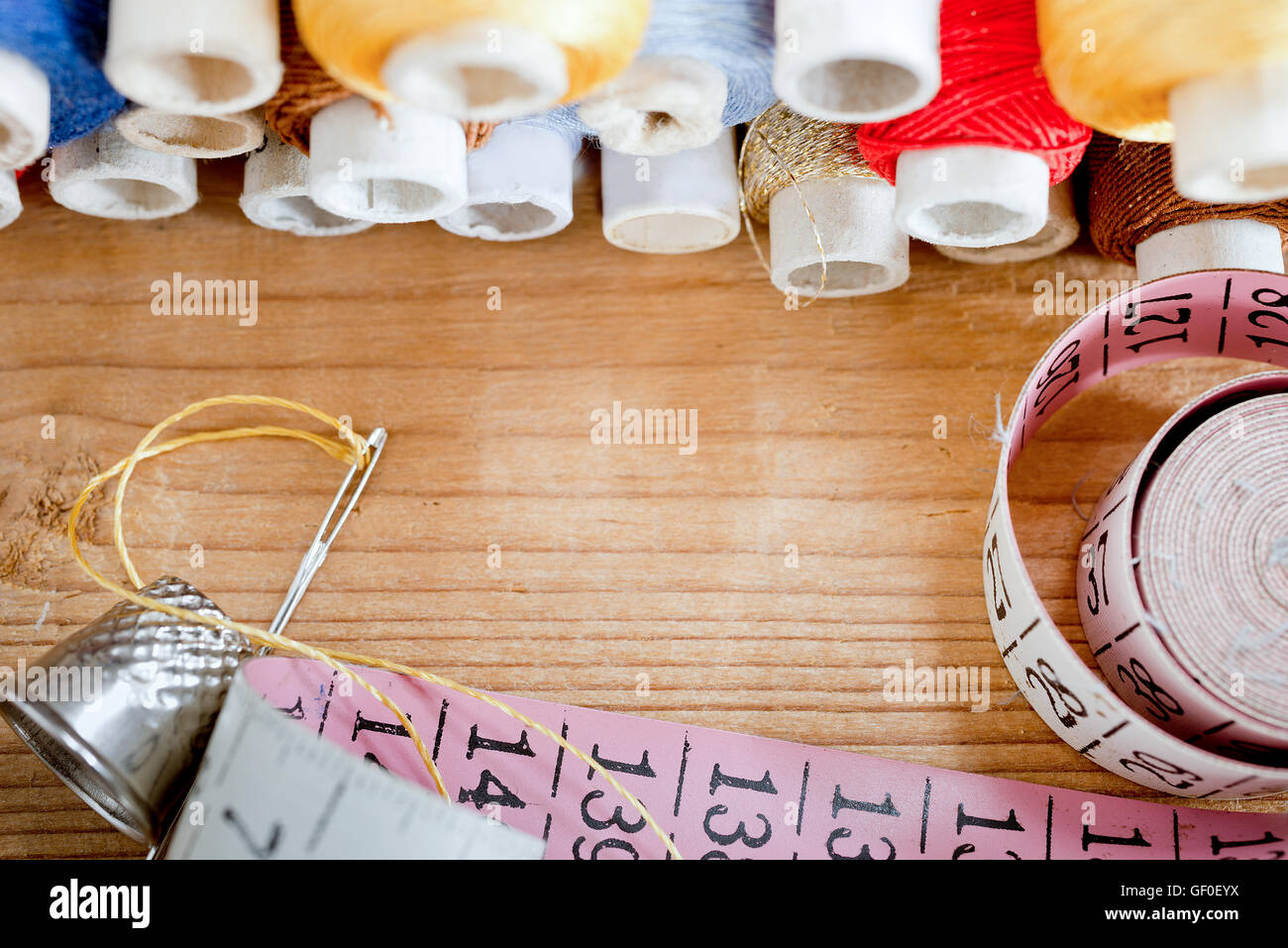 needle with thread and tape measure on the wooden desk Stock Photo - Alamy