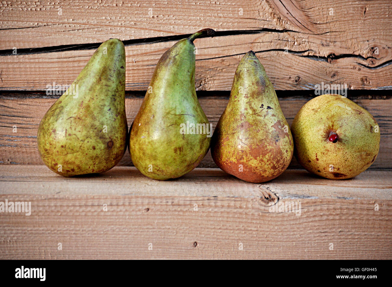 four mature pears in a row on wood Stock Photo - Alamy