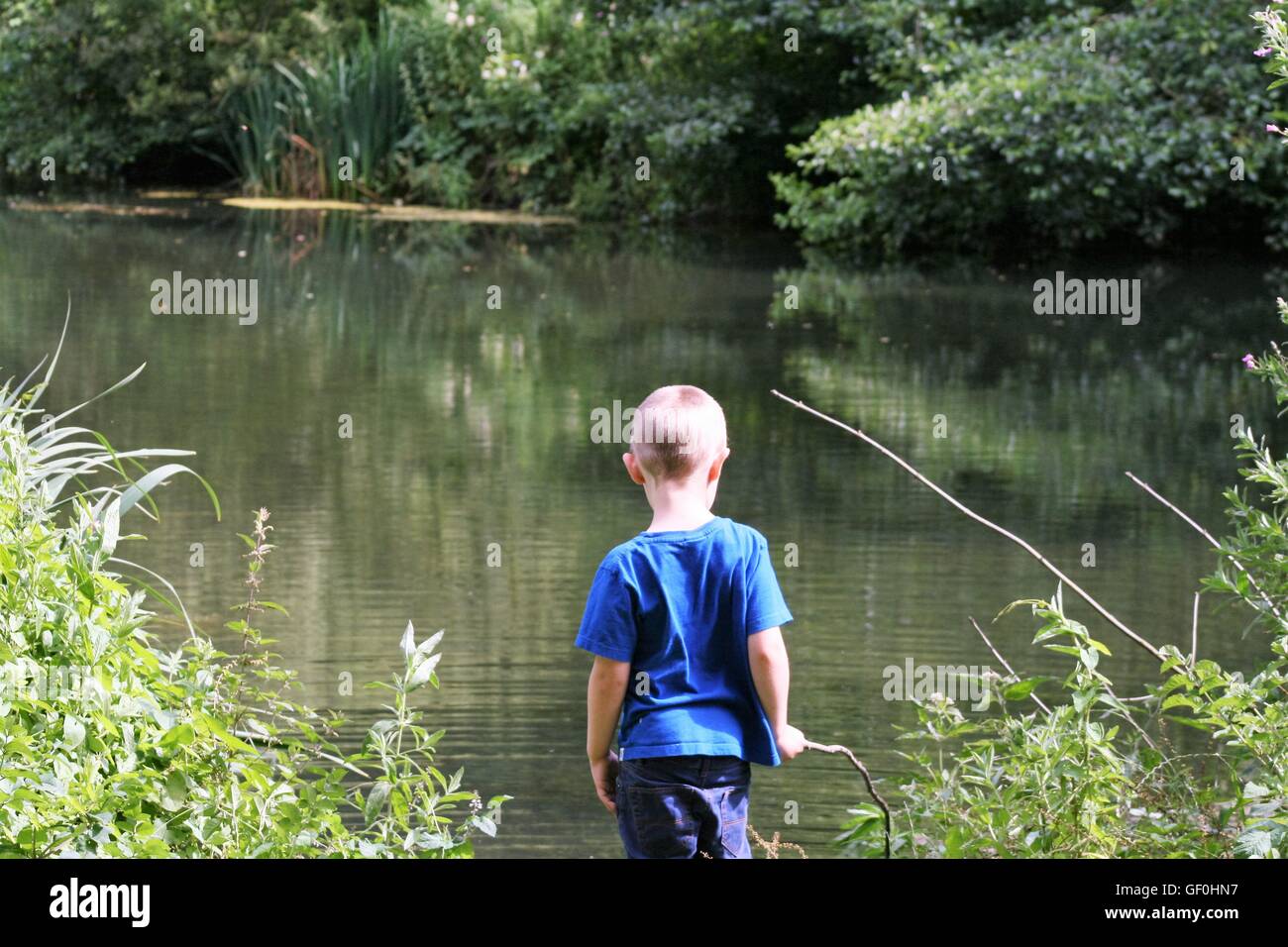 Boy stood at lake Stock Photo - Alamy