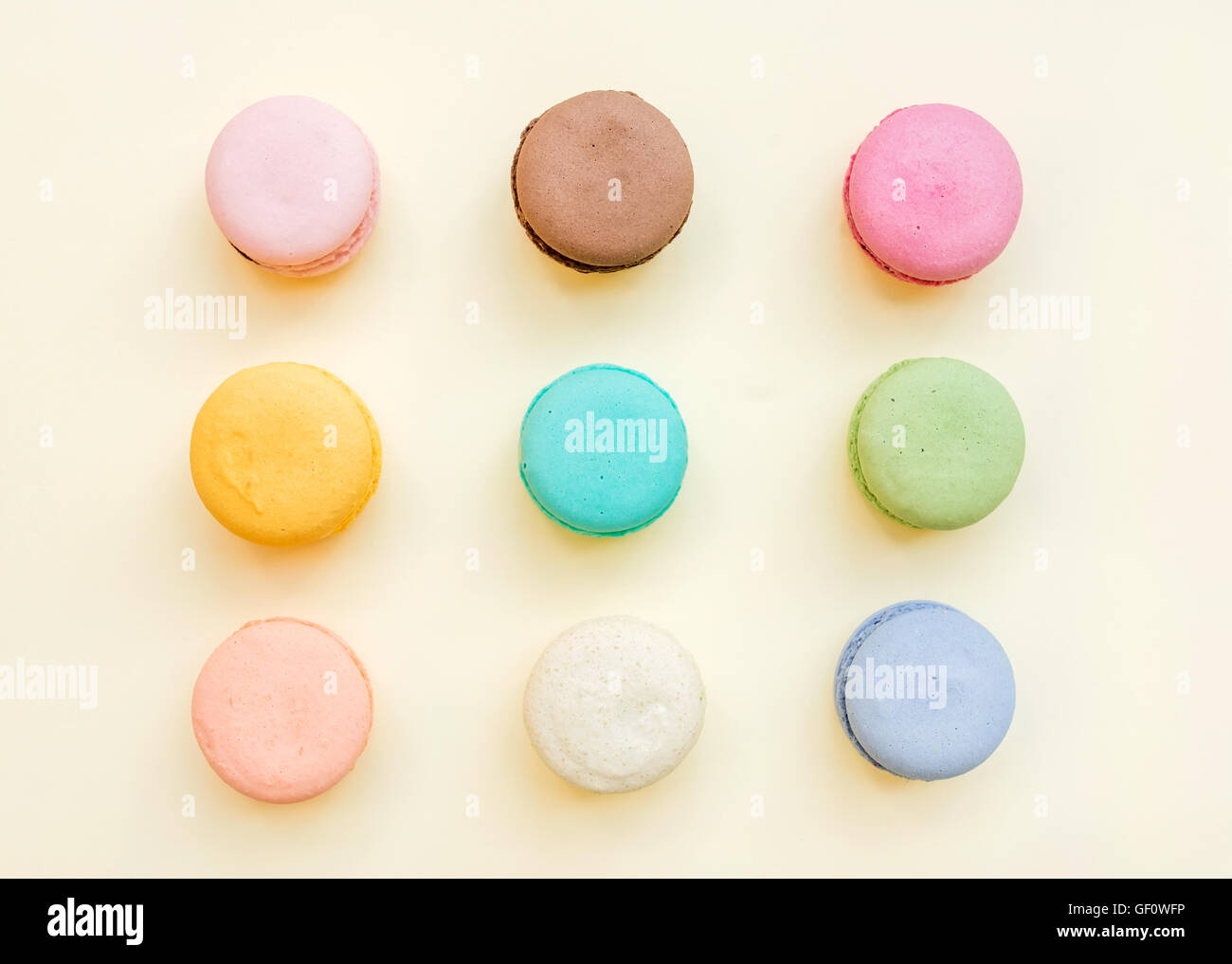 Sweet colorful French macaroon biscuits on pastel yellow background ...