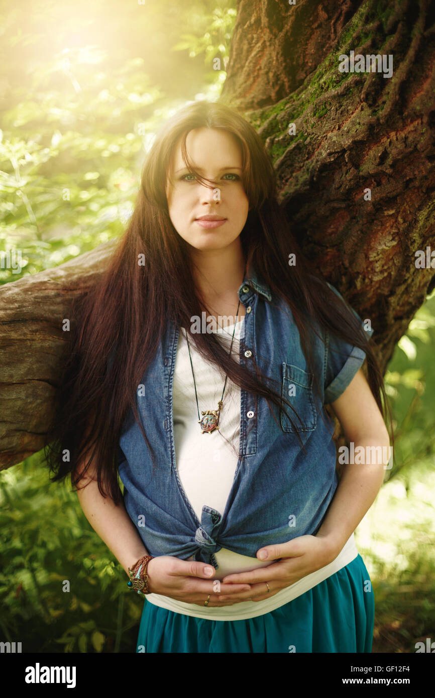 Young woman expecting baby. Calm mood, summer outdoor, looking in ...
