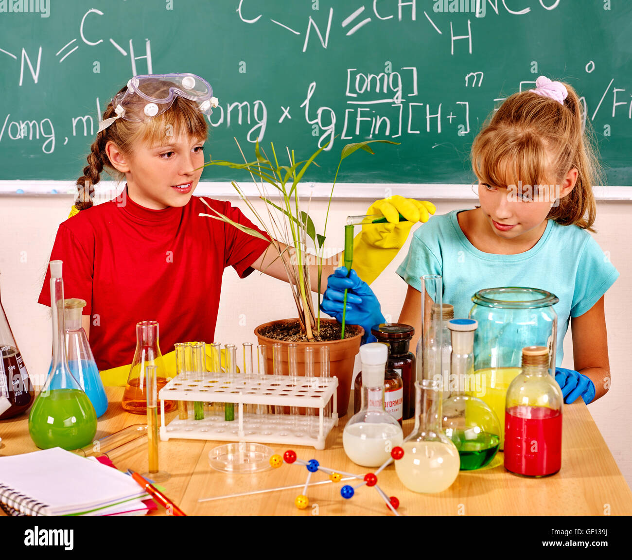 Children holding flask and plant in biology class Stock Photo - Alamy