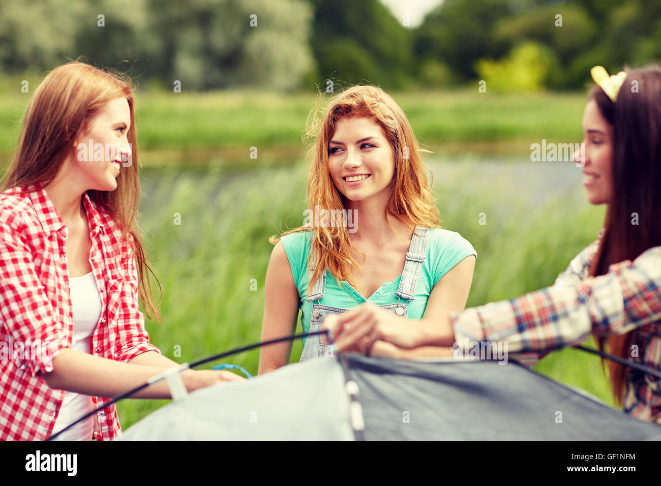 group of smiling friends setting up tent outdoors Stock Photo - Alamy
