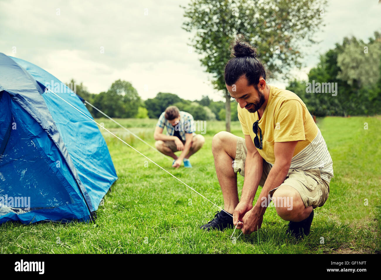 smiling friends setting up tent outdoors Stock Photo - Alamy