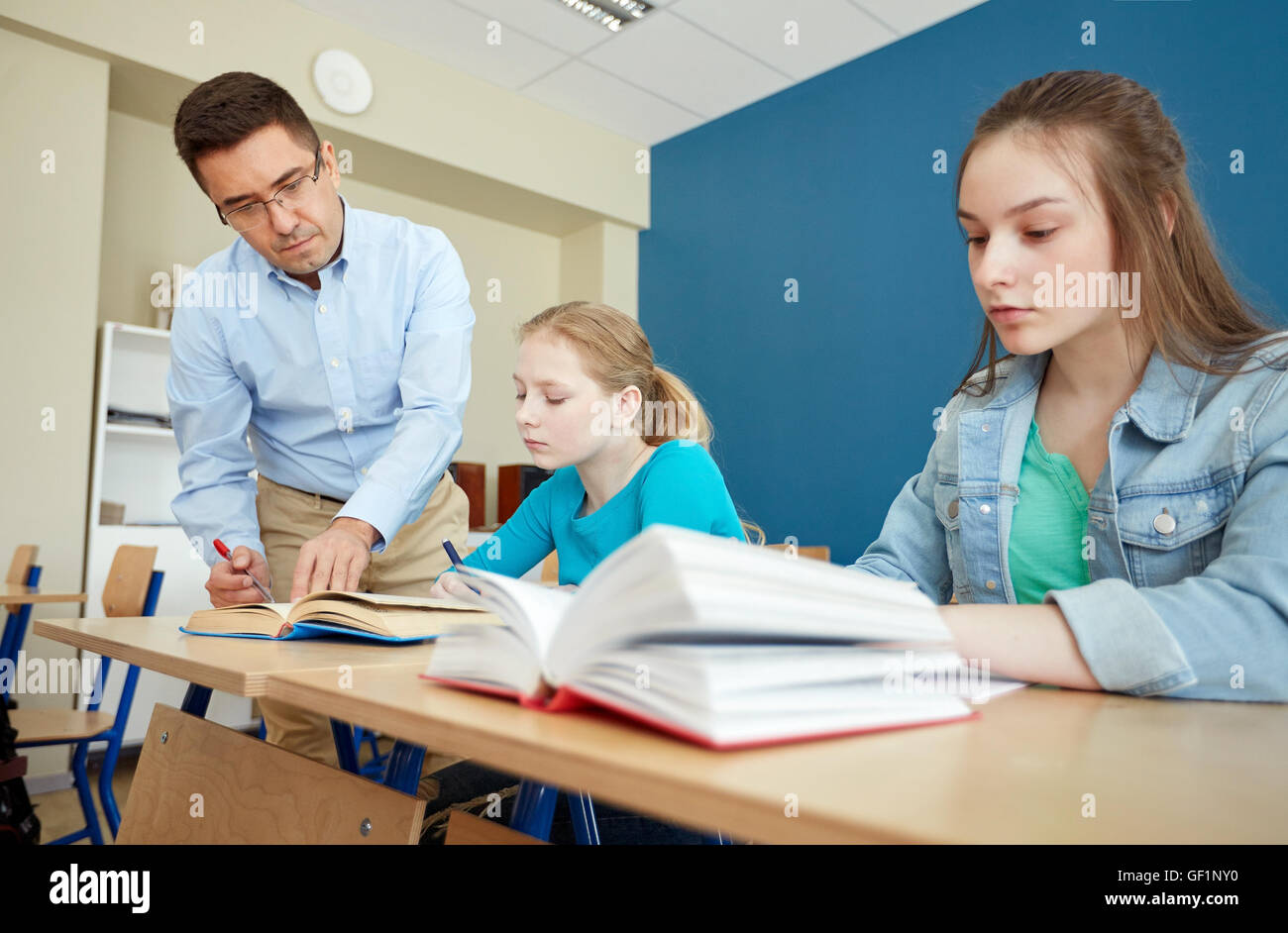 teacher helping students with task at school Stock Photo - Alamy