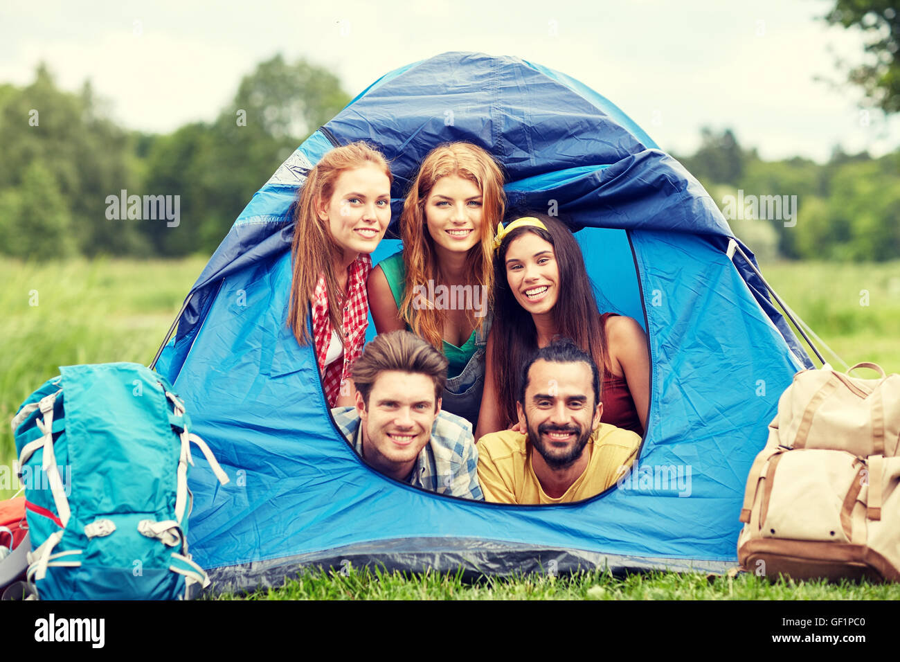 happy friends with backpacks in tent at camping Stock Photo - Alamy