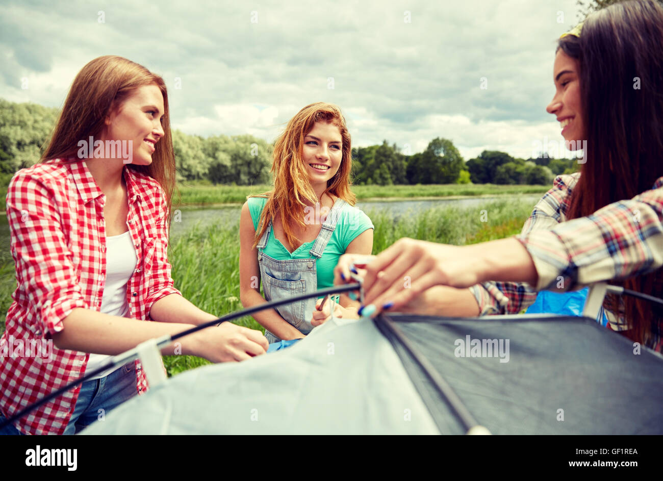 smiling friends setting up tent outdoors Stock Photo - Alamy