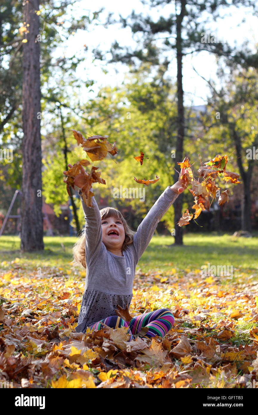 happy little girl throws leaves Stock Photo - Alamy