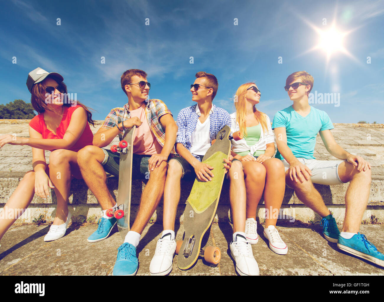 group of smiling friends sitting on city street Stock Photo - Alamy