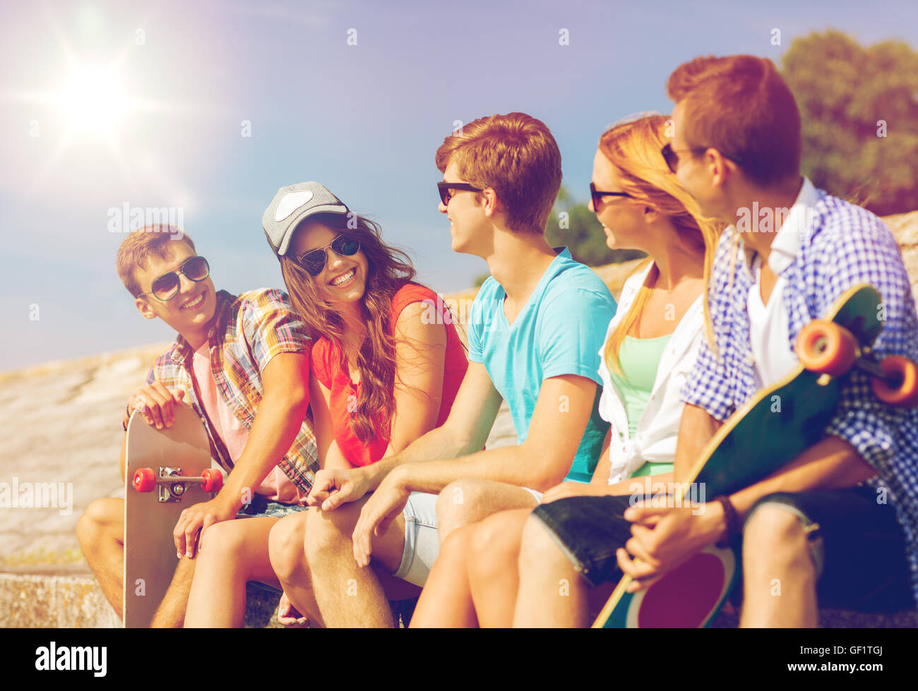 group of smiling friends sitting on city street Stock Photo - Alamy