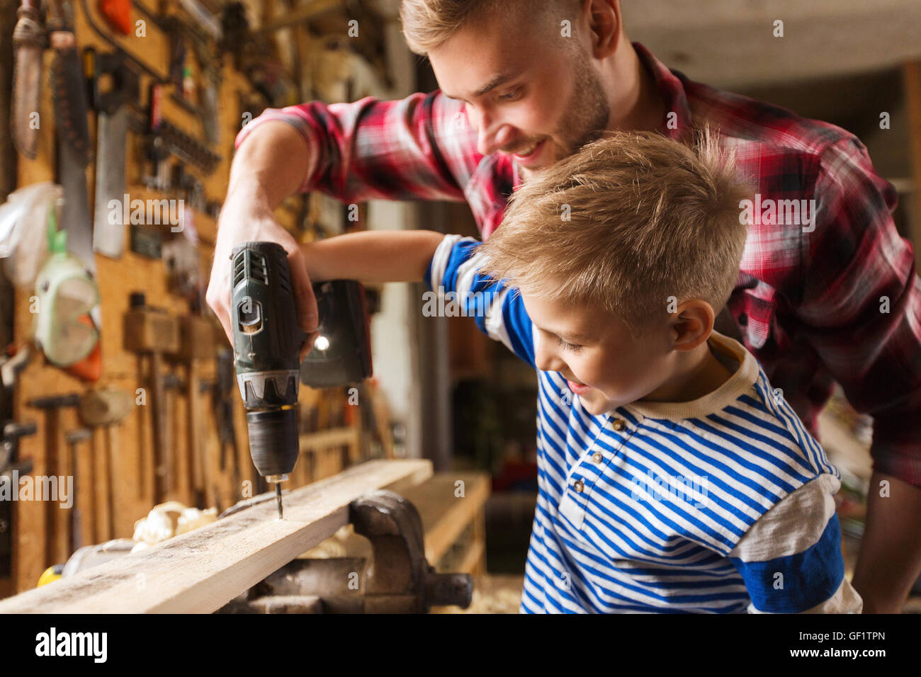 father and son with drill working at workshop Stock Photo - Alamy