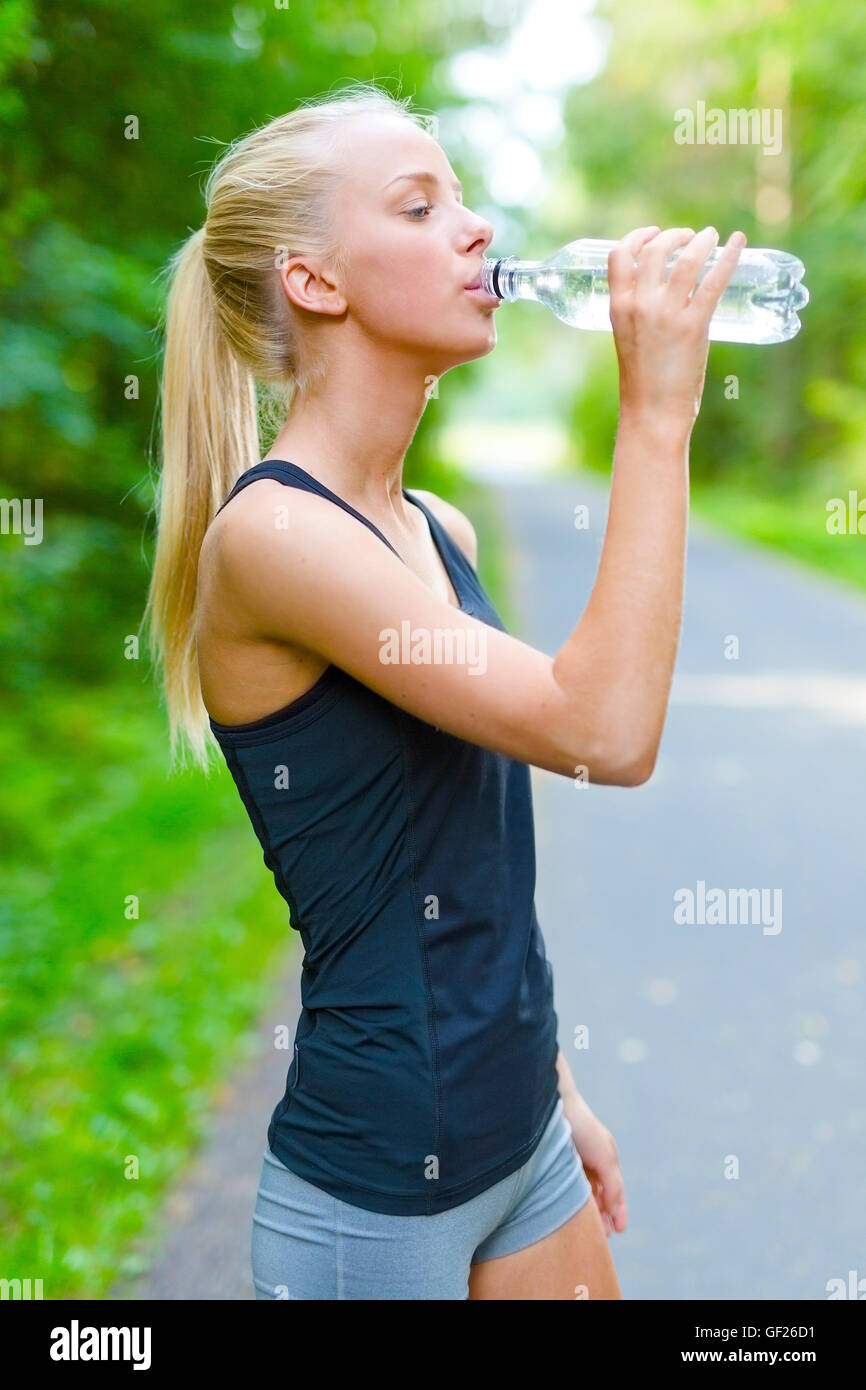 Female runner drinking water after running Stock Photo - Alamy