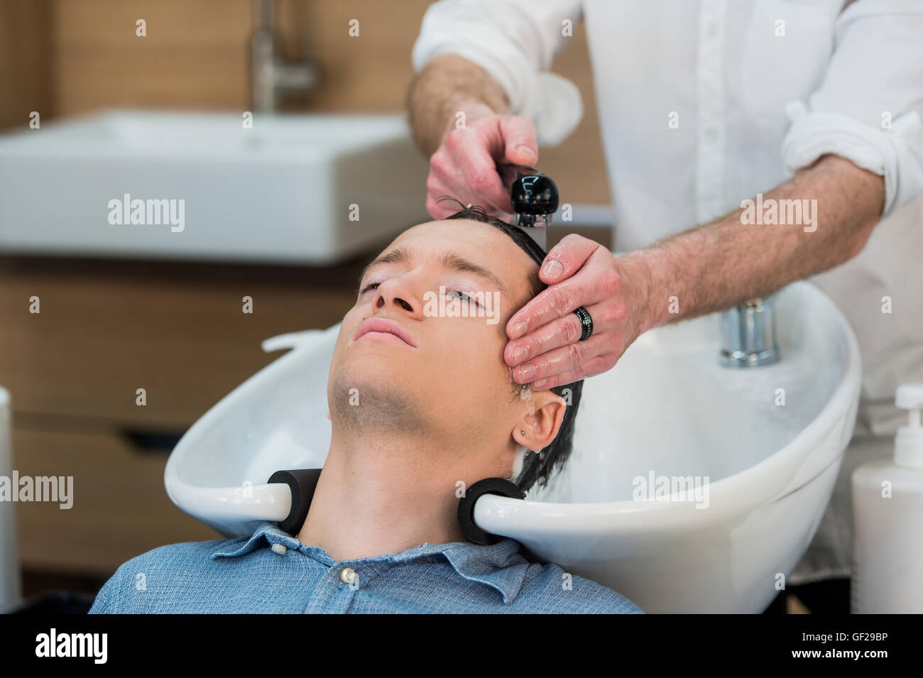 Close-up of a young man having his hair washed in hairdressing salon ...