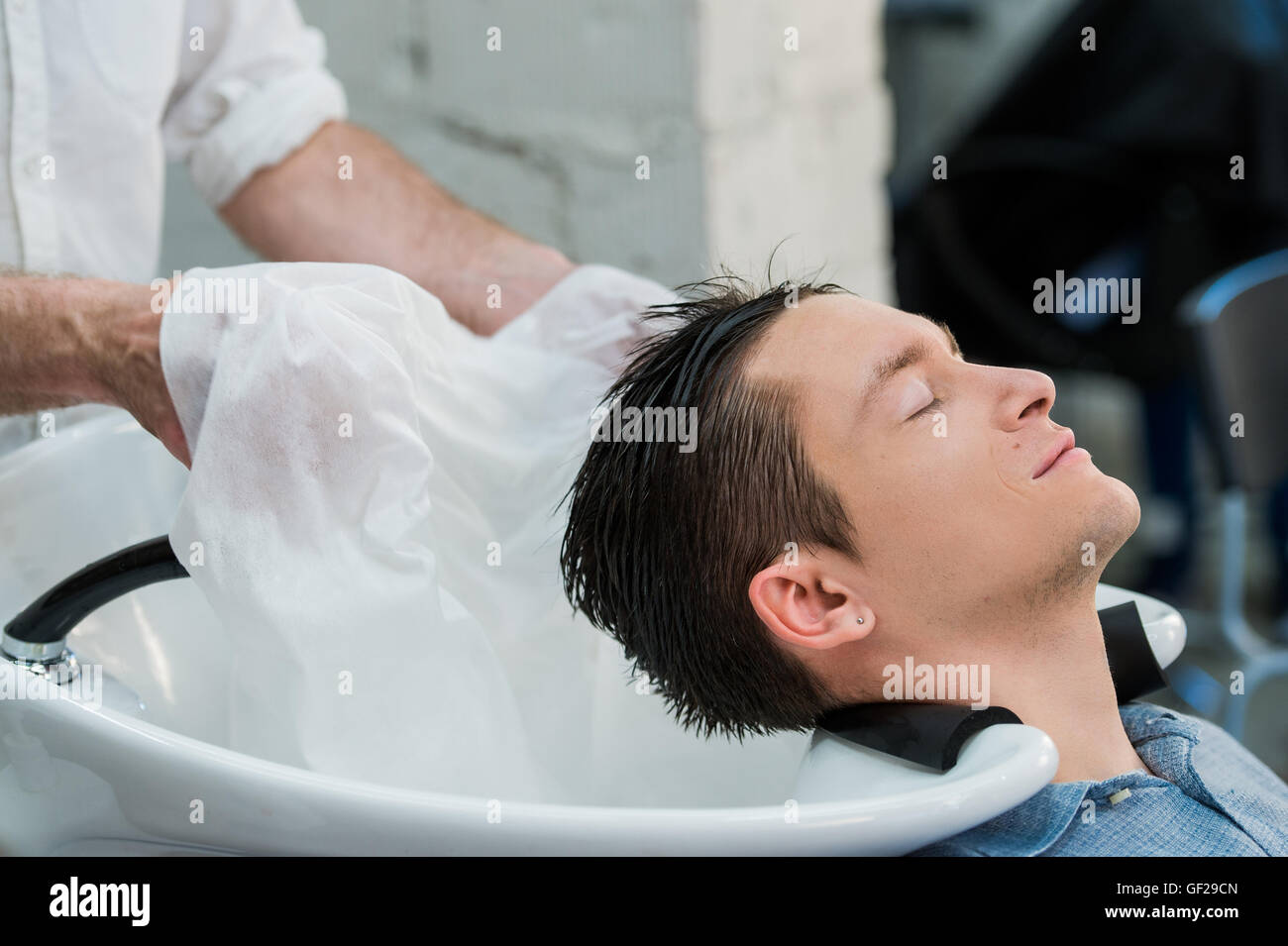 Hairstylist washing client's hair in barber shop Stock Photo - Alamy