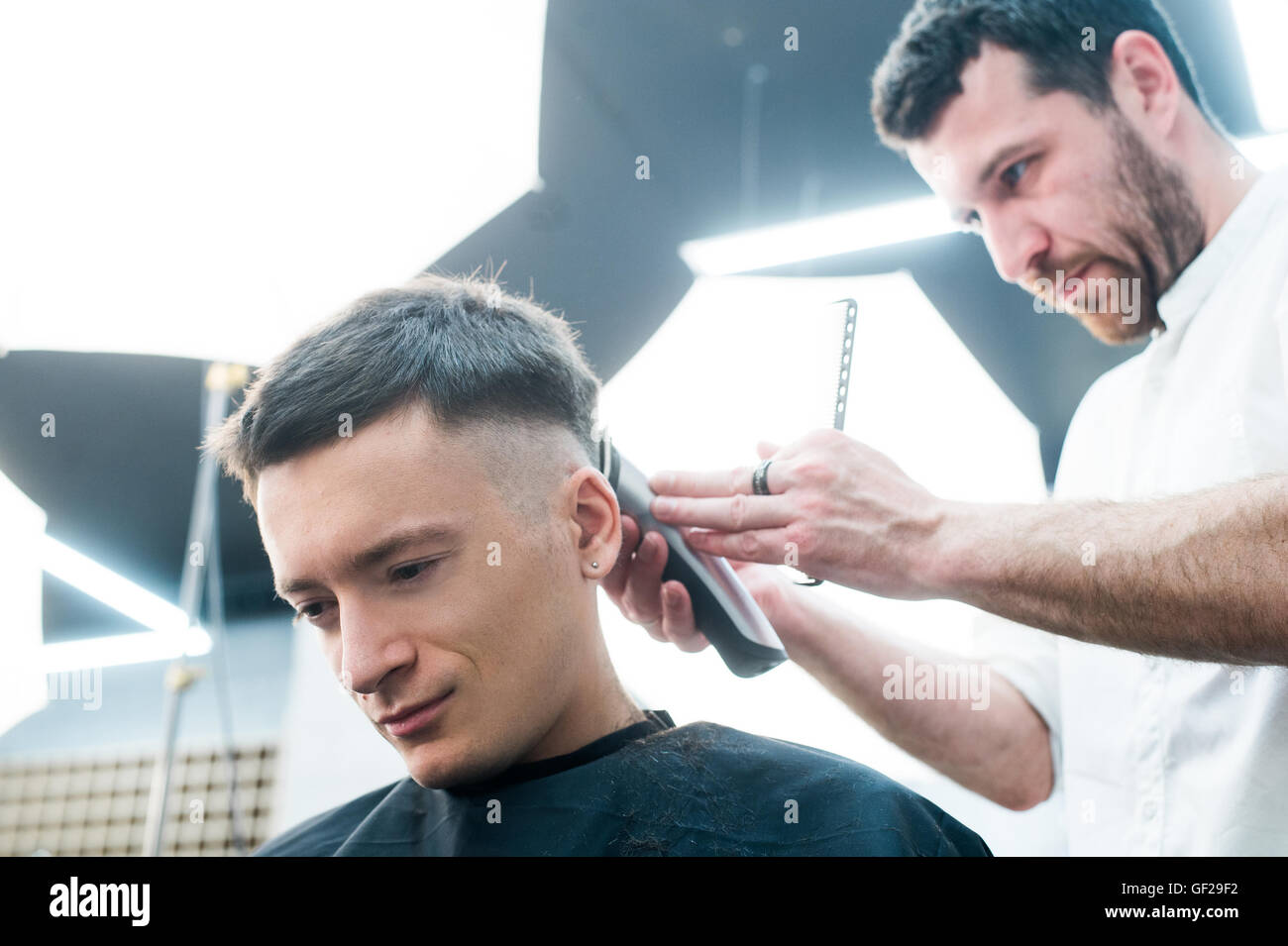 Professional styling. Close up side view of young man getting haircut ...