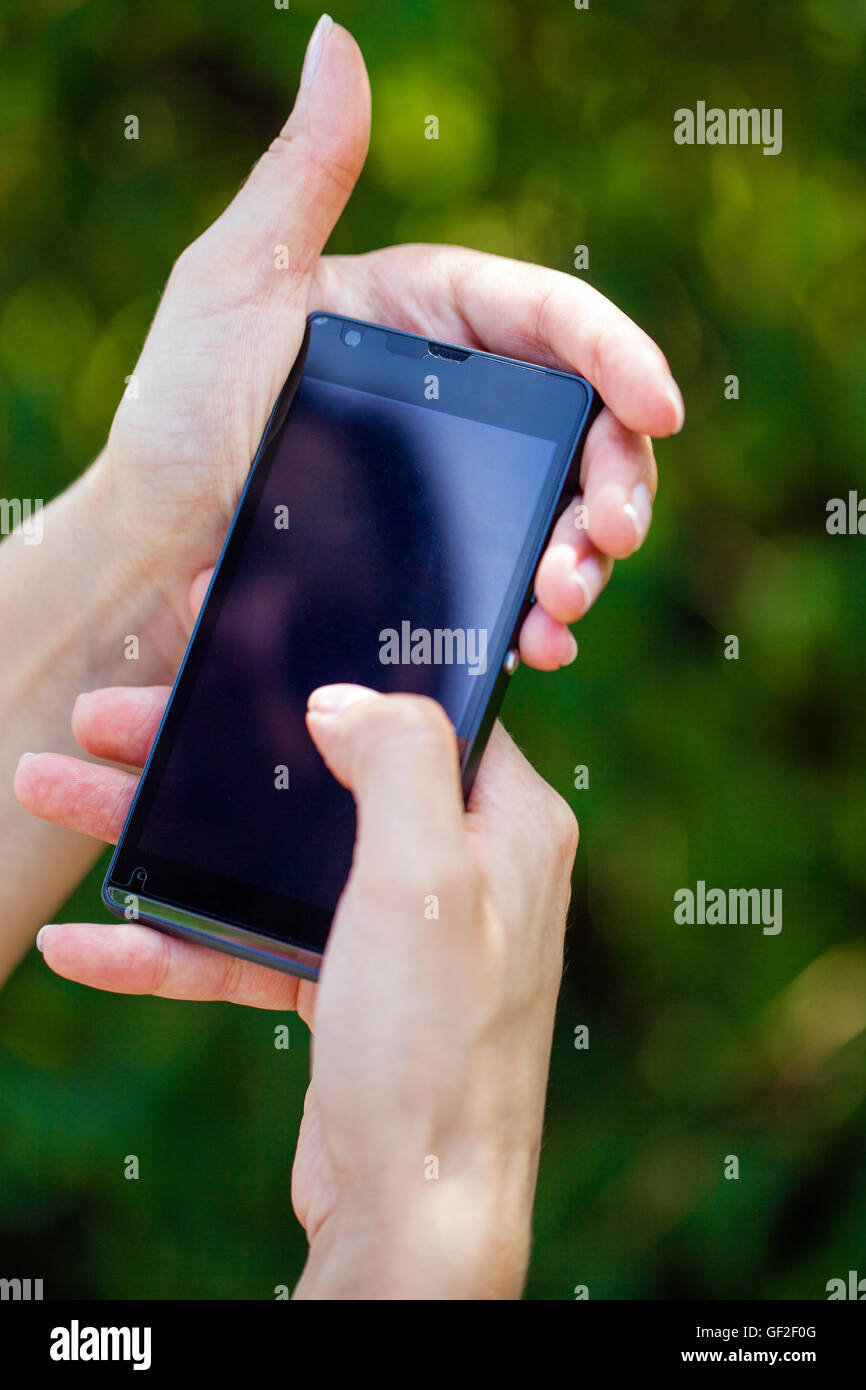 Side view of a woman's hand holding a modern slick smartphone while ...