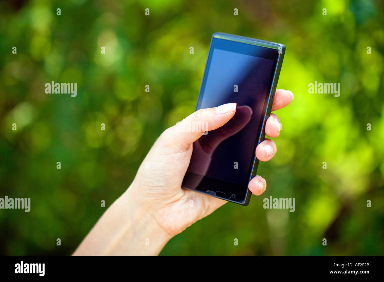 Side view of a woman's hand holding a modern slick smartphone while ...