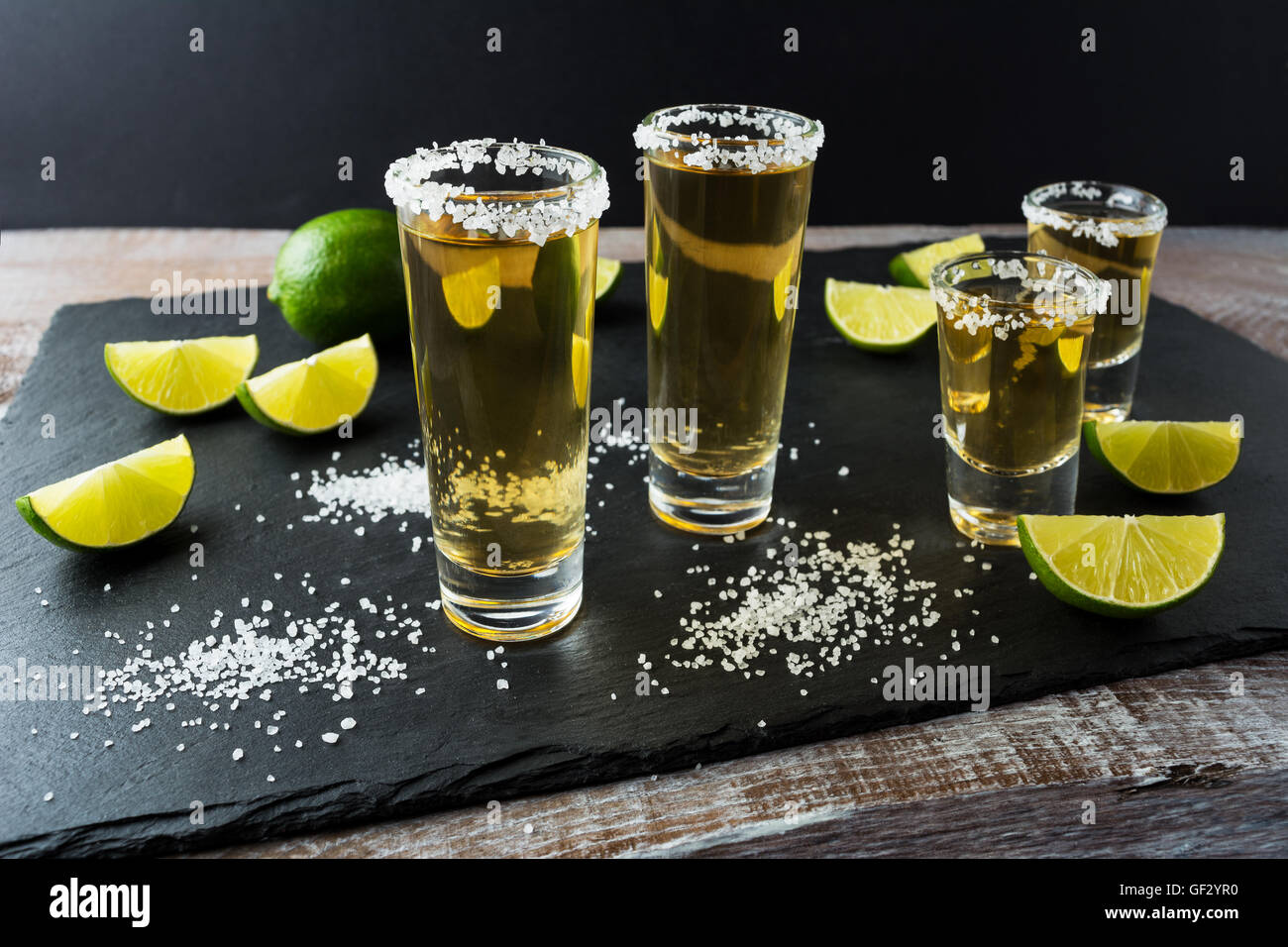 Tequila shots with lime on black stone background. Strong alcohol drink ...