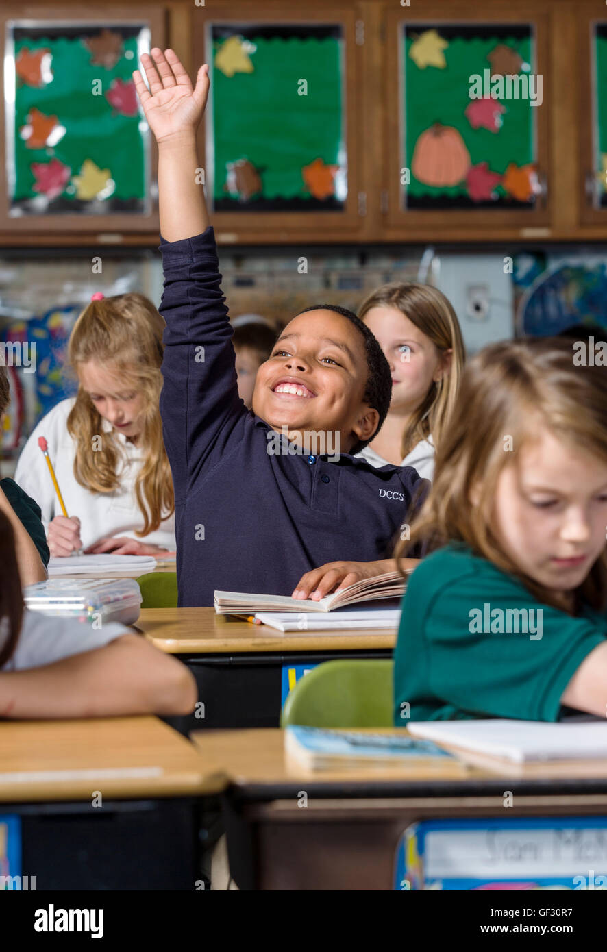Children raising hands in private elementary school classroom with ...