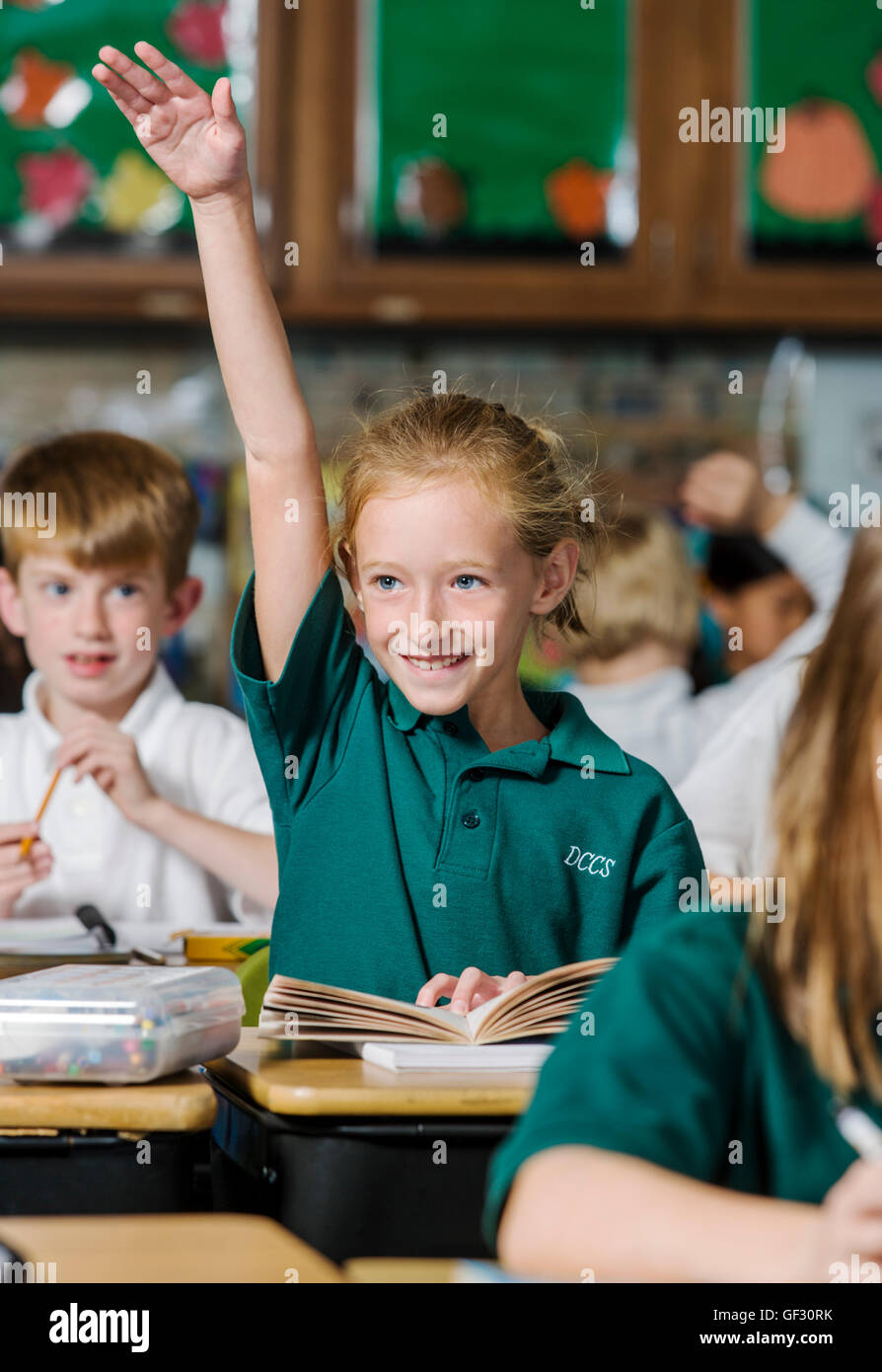 Children raising hands in private elementary school classroom with ...