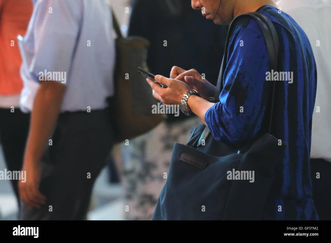 People look at their smartphones in Tokyo, Japan on July 27, 2016 ...