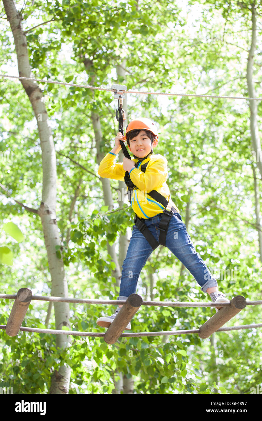 Little Chinese boy playing in tree top adventure park Stock Photo - Alamy