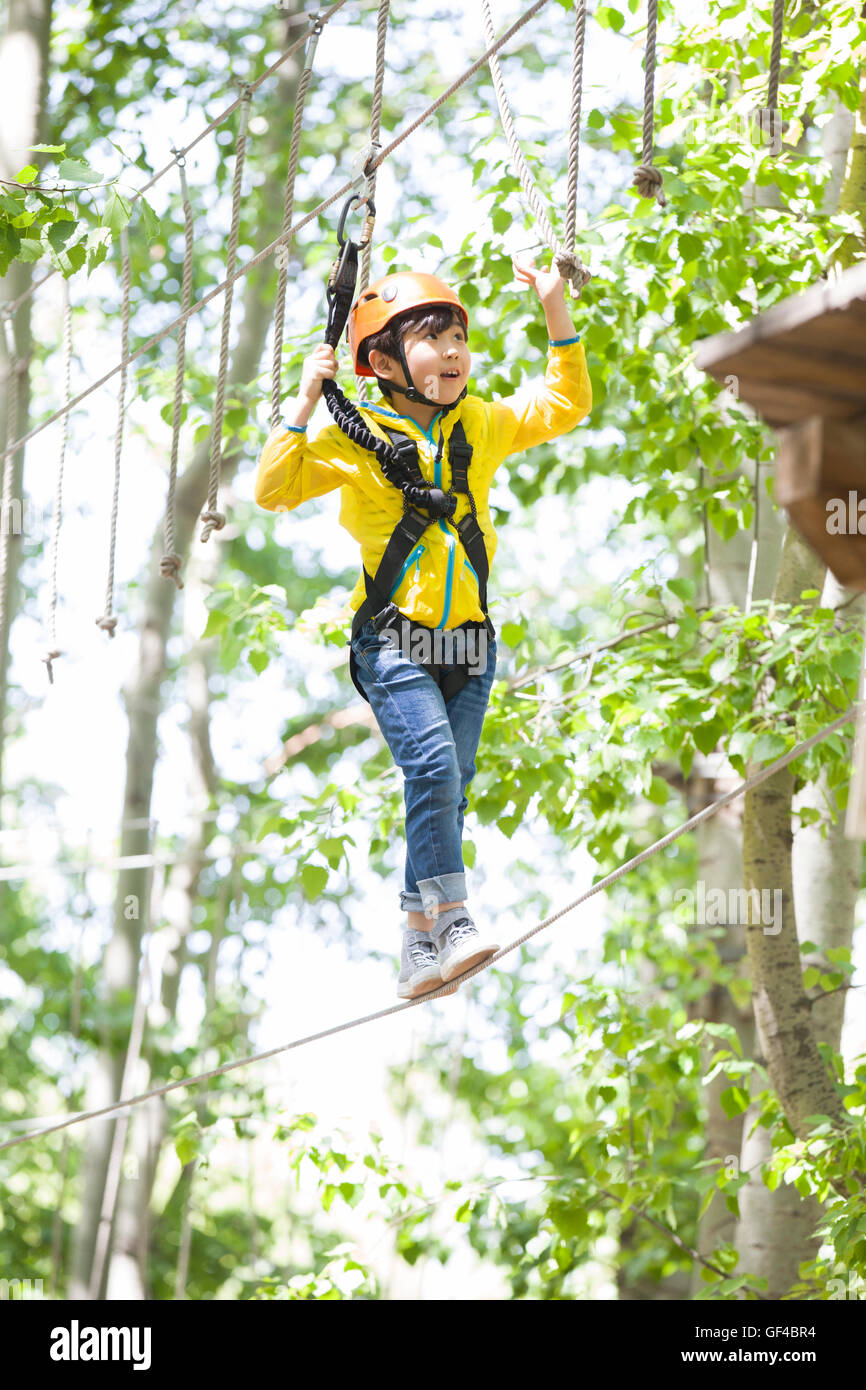 Little Chinese boy playing in tree top adventure park Stock Photo - Alamy
