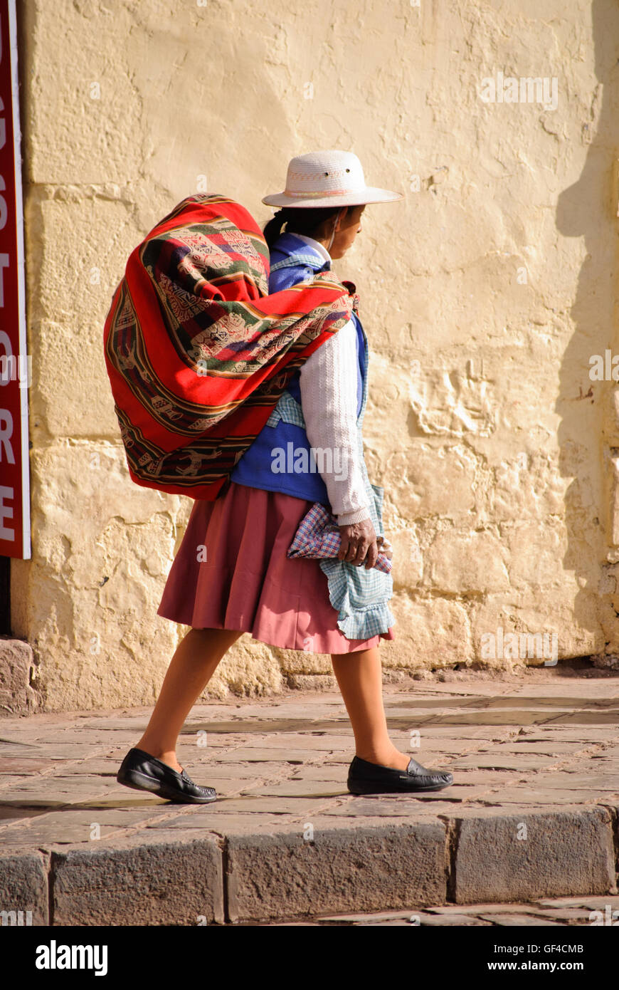 An Andean Indian woman in half traditional costume walking on a street ...