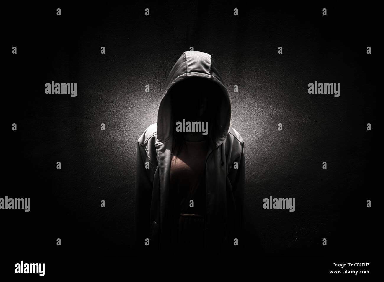 Woman wearing hoodie hiding in the dark,Scary background for book cover ...