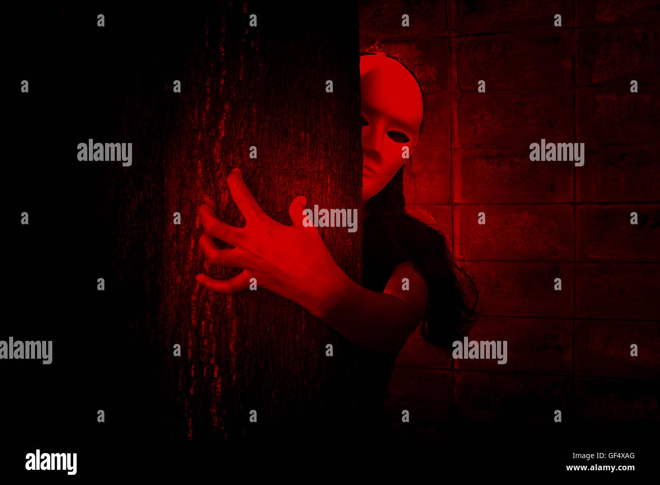 Mysterious woman in black dress wearing white mask hiding behind tree ...