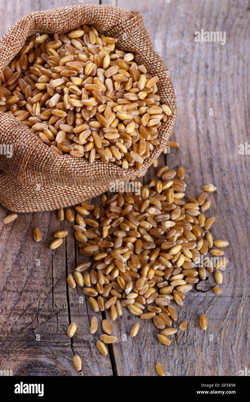 Wheat in small burlap sack on rustic wooden background Stock Photo - Alamy