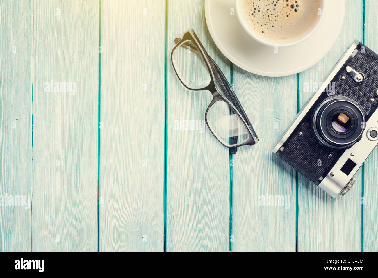 Sunny table with camera, glasses and coffee. Top view with copy space ...