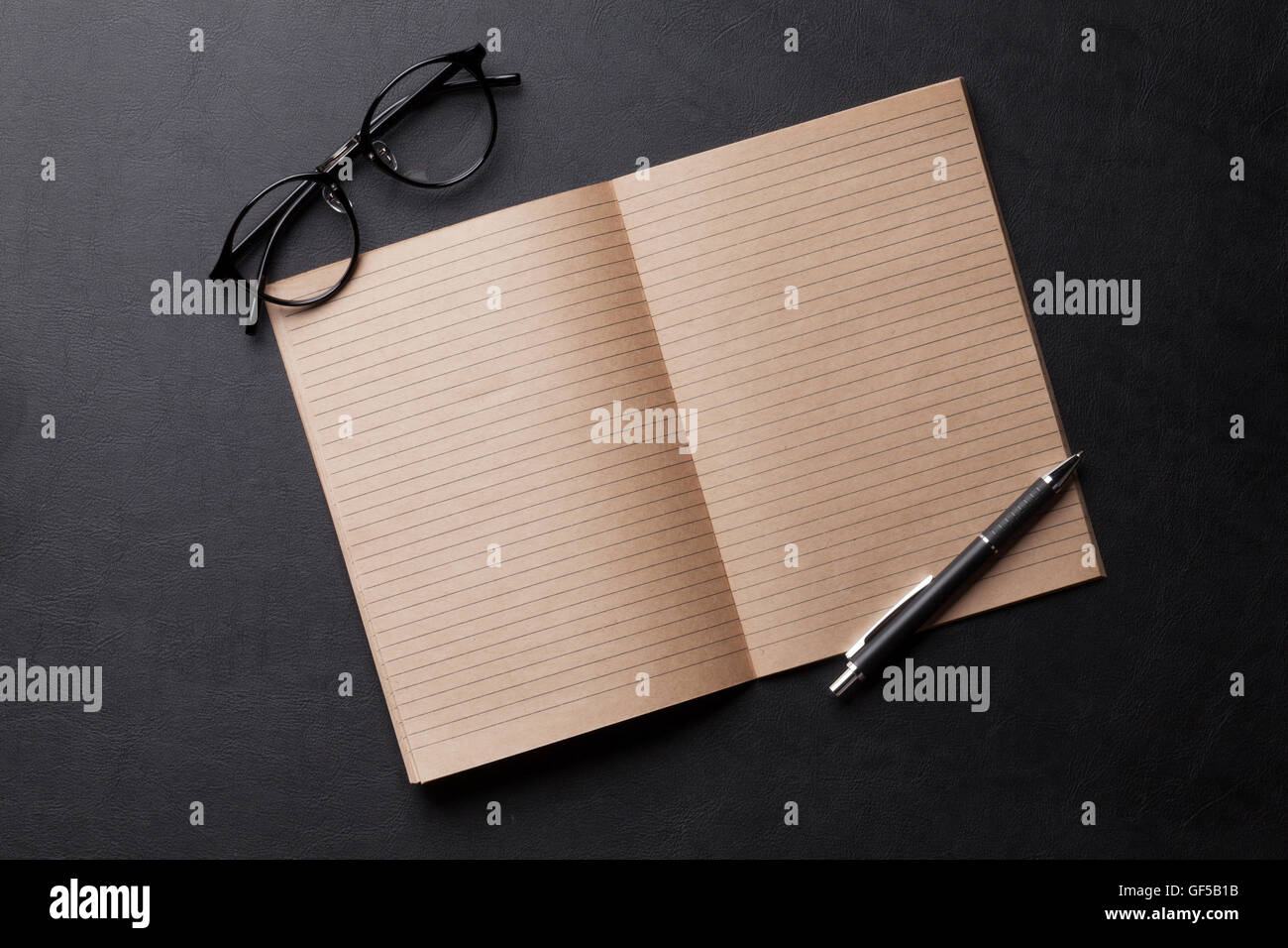 Office desk with notepad and glasses over leather texture. Top view ...