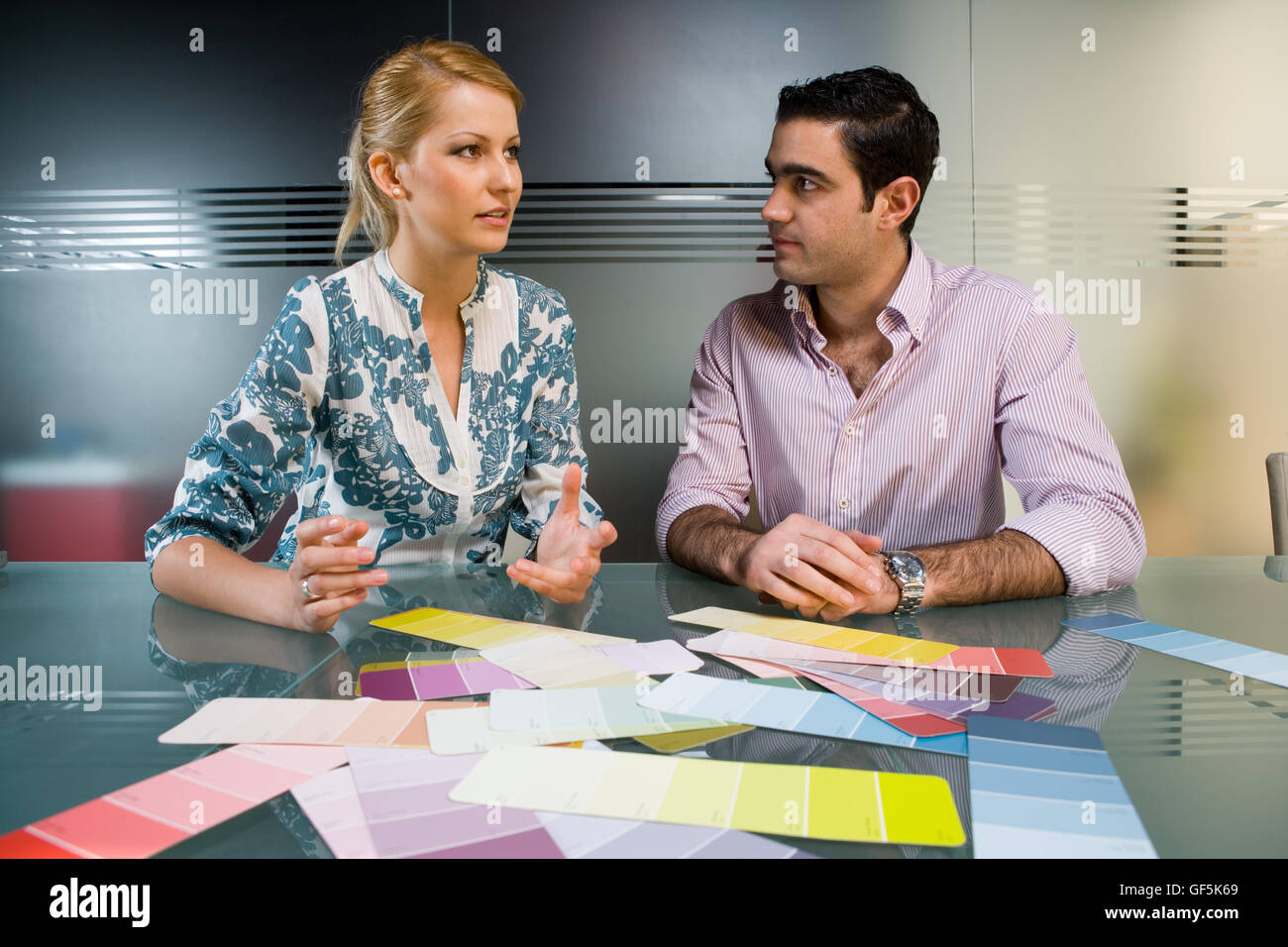 A male and female business executives discussing color schemes in a ...