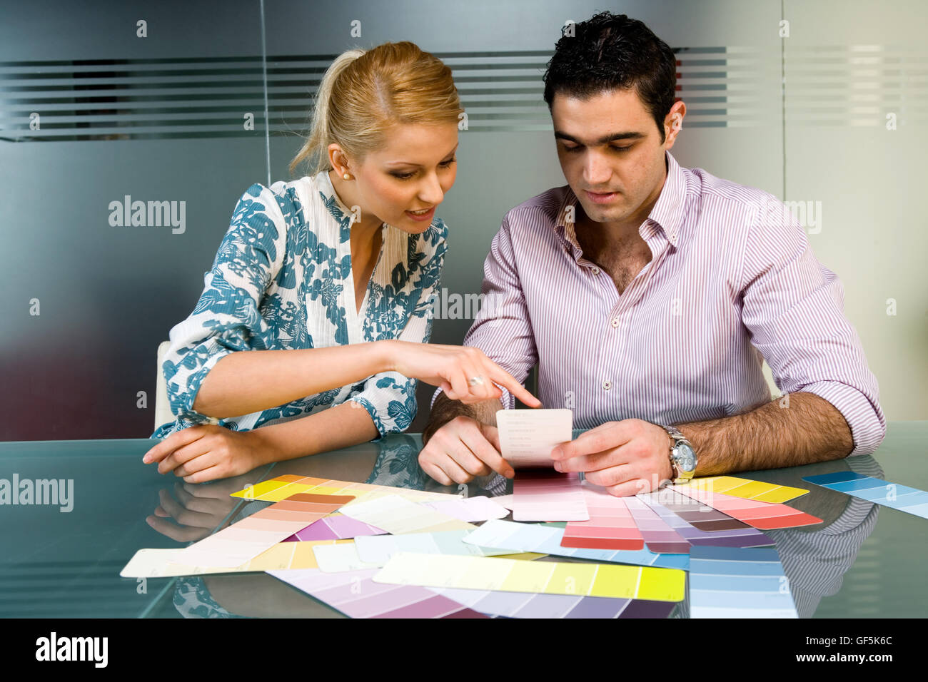 A male and female business executives discussing color schemes in a ...