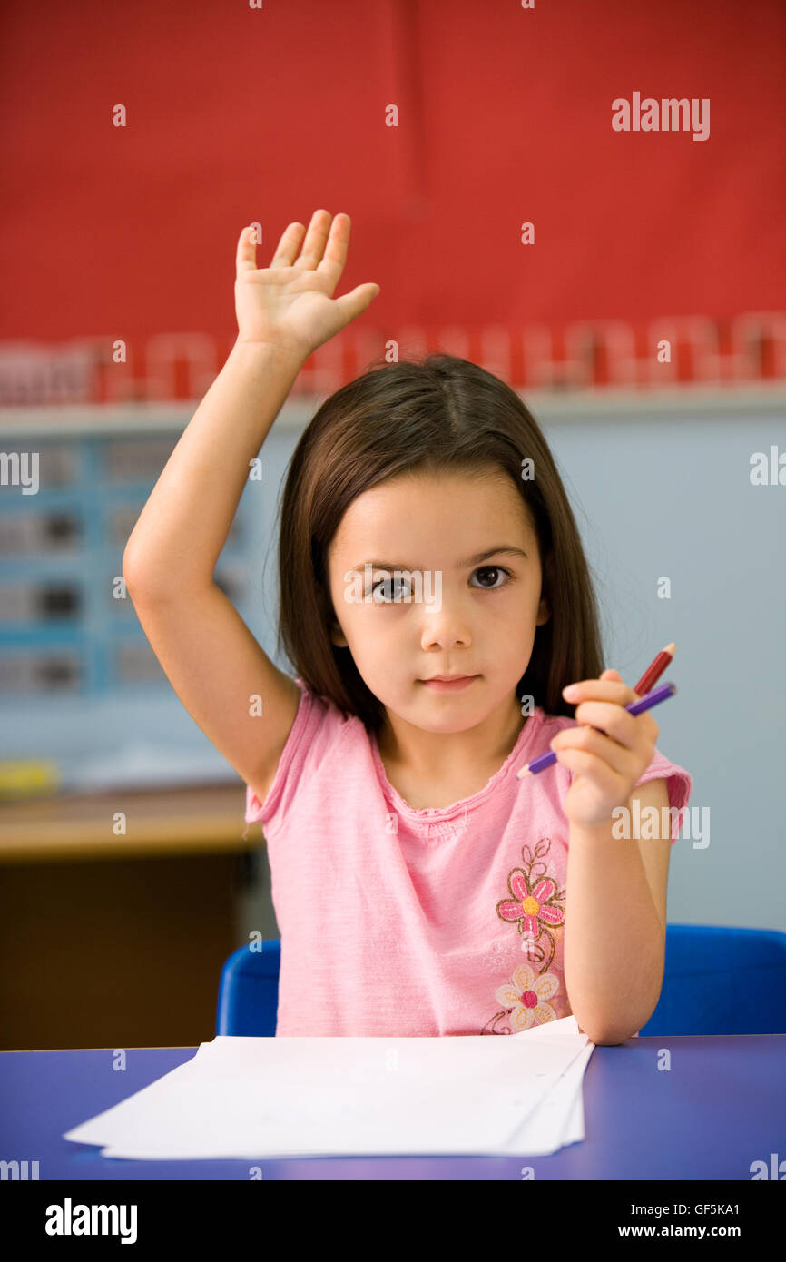A small girl raising hand in classroom Stock Photo - Alamy