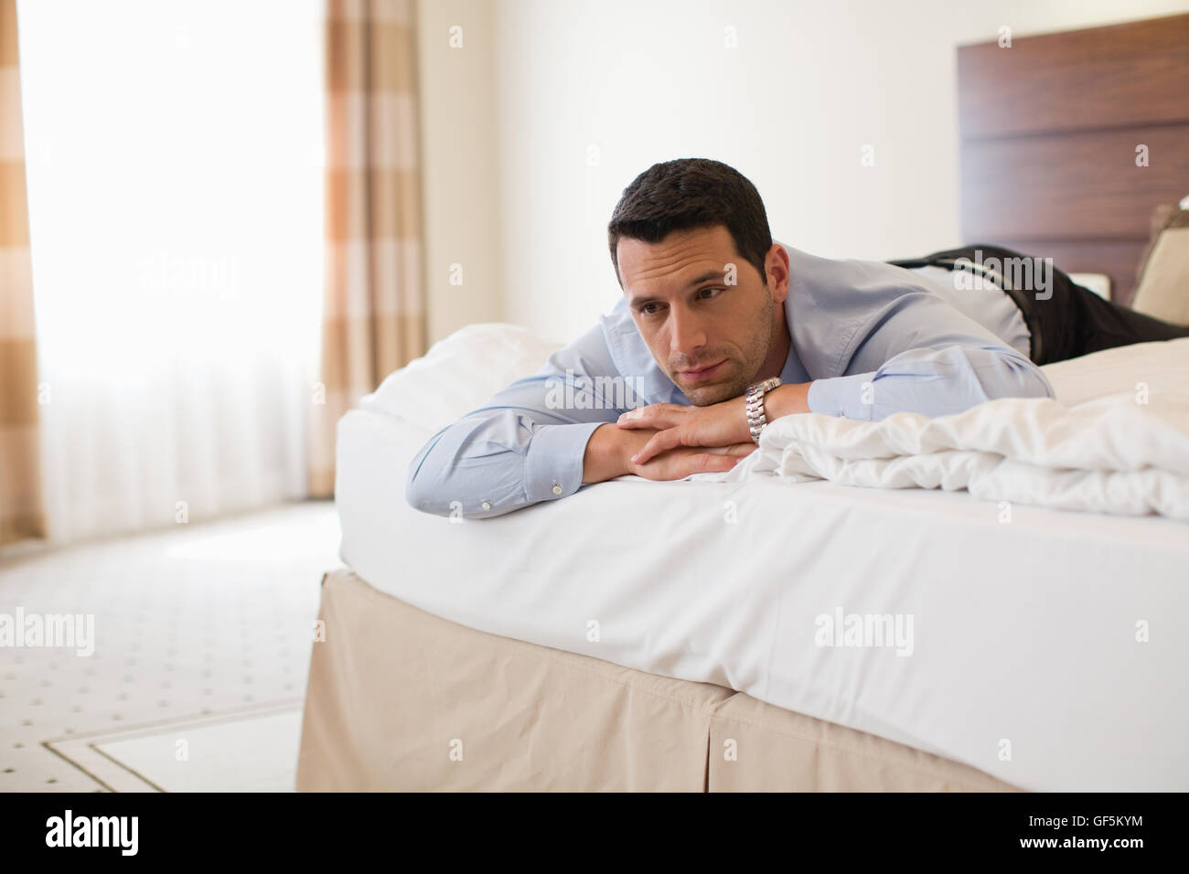 Man relaxing on bed in hotel room Stock Photo - Alamy